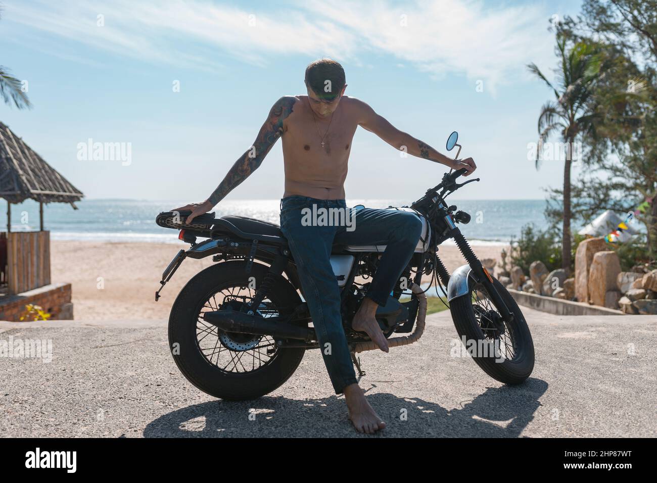 Young shirtless caucasian guy with full-arm tattoo sitting on ...