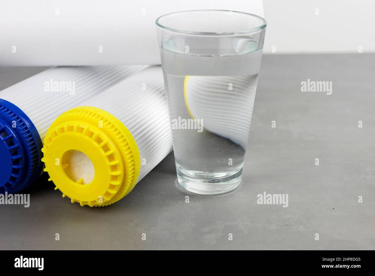 A glass of clean water next to the water purification filter. The ...