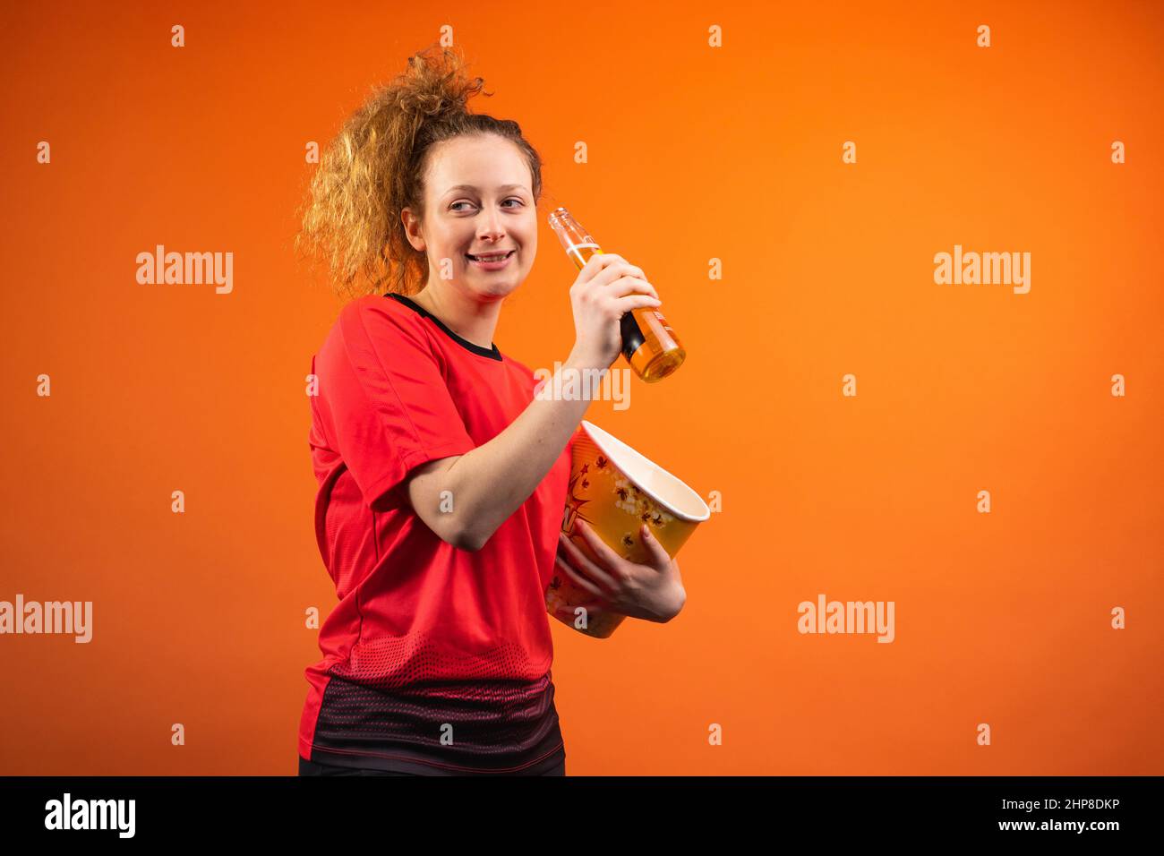 Cool woman football fan eating popcorn and drinking beer while cheering ...