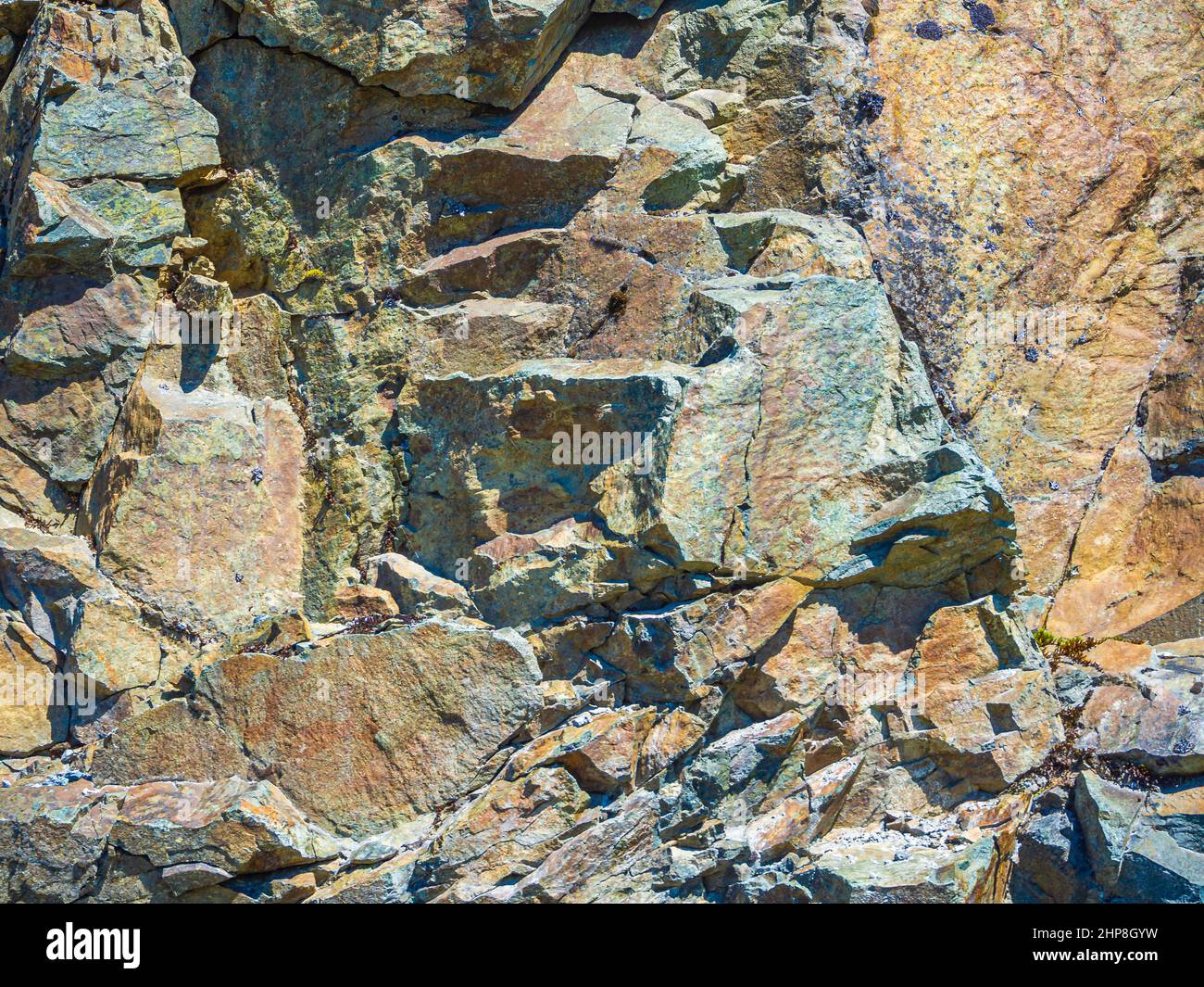 Stone rock wall texture with orange and yellow moss and lichen colors ...