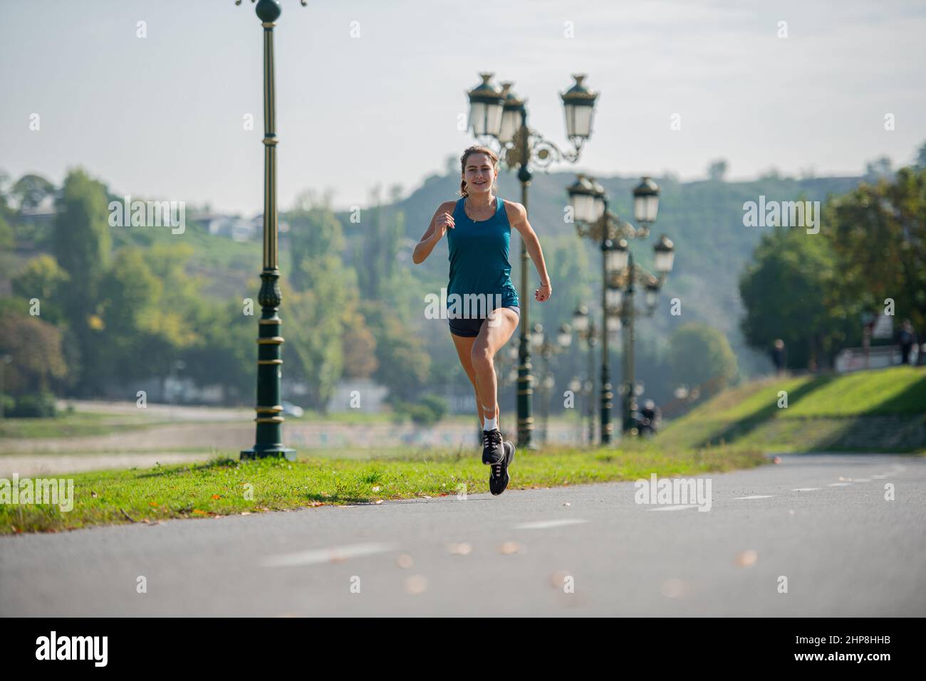 Attractive and beautiful girl is running on the track while warming up ...