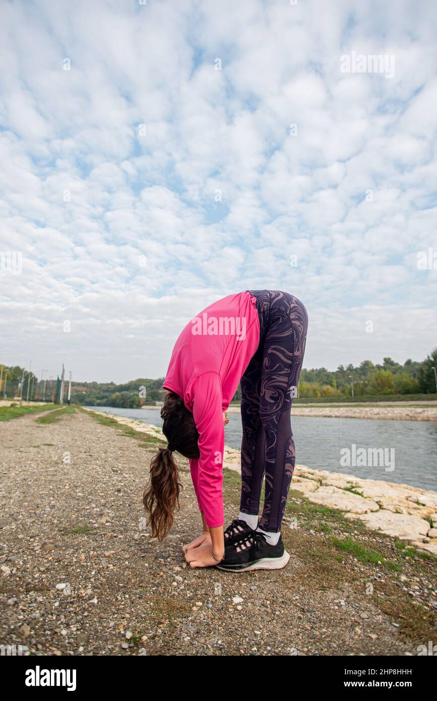 Amazing and beautiful girl is stretching her back and legs before her ...