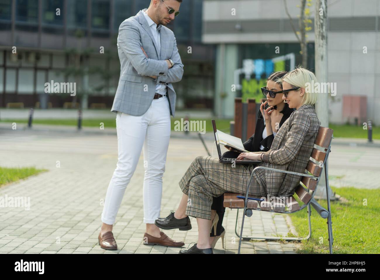 Three business people are working from outside while sitting on the ...