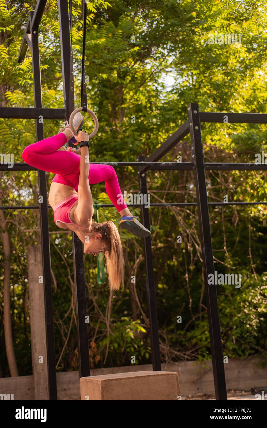 Fit and attractive young girl is trying to flip over while holding ...