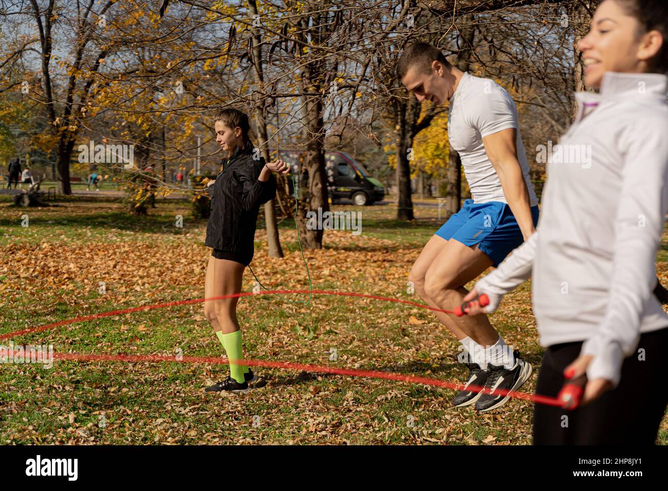 Three attractive and beautiful fit friends are jumping on the rope and ...