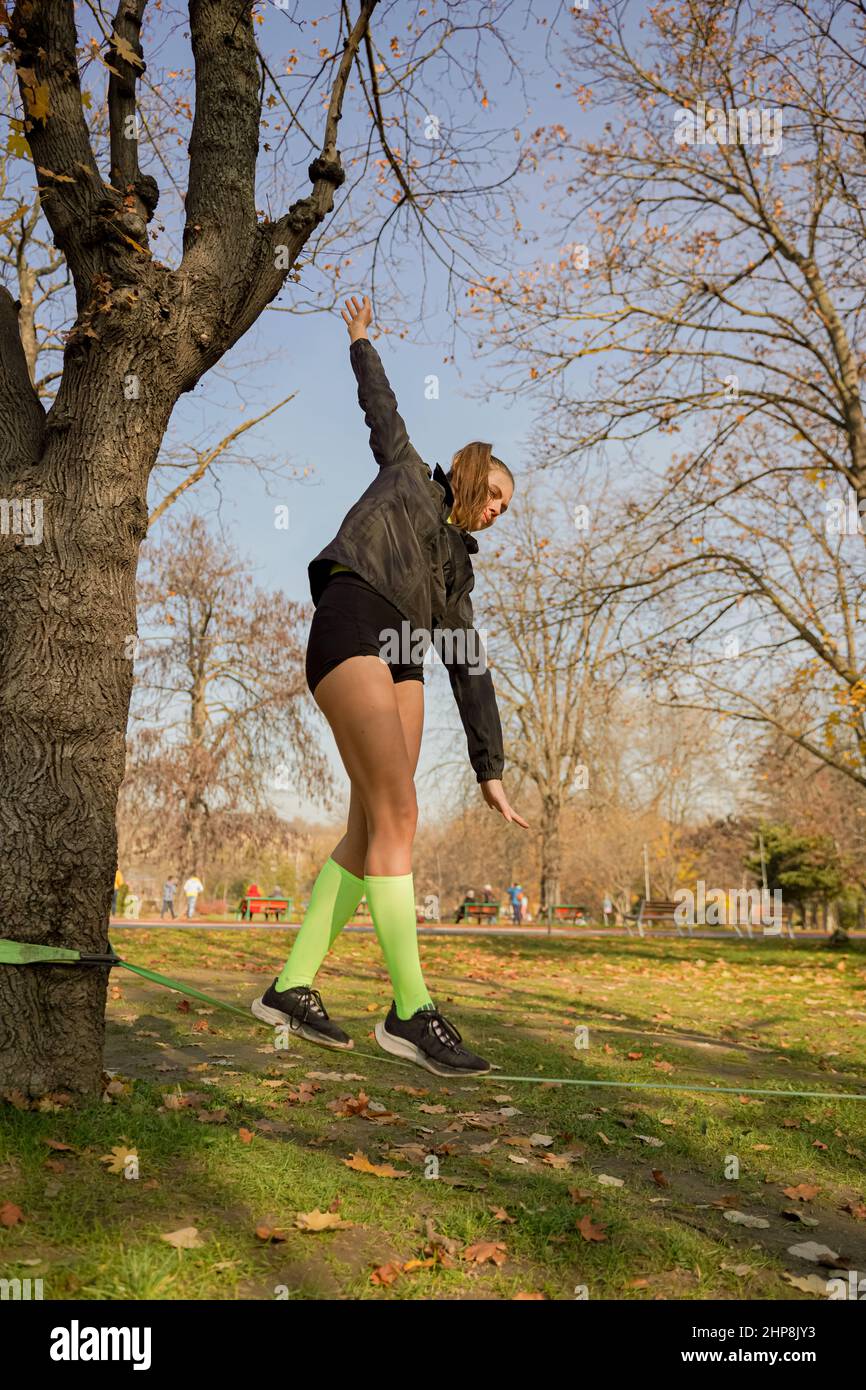 Attractive and beautiufl fit girl is balancing on the rope and smiling ...