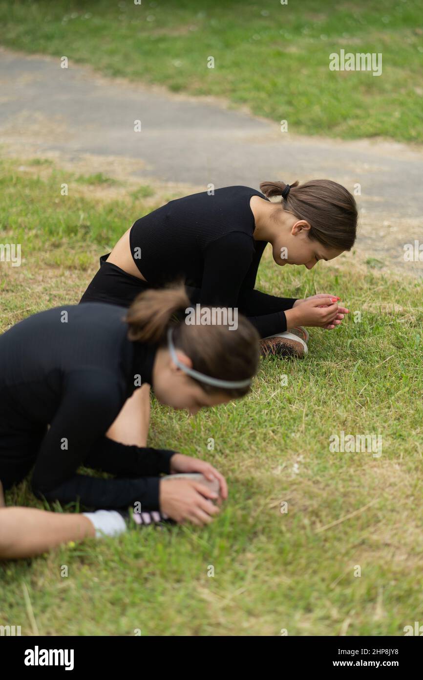 Two attractive girls are stretching together on the ground, selective ...