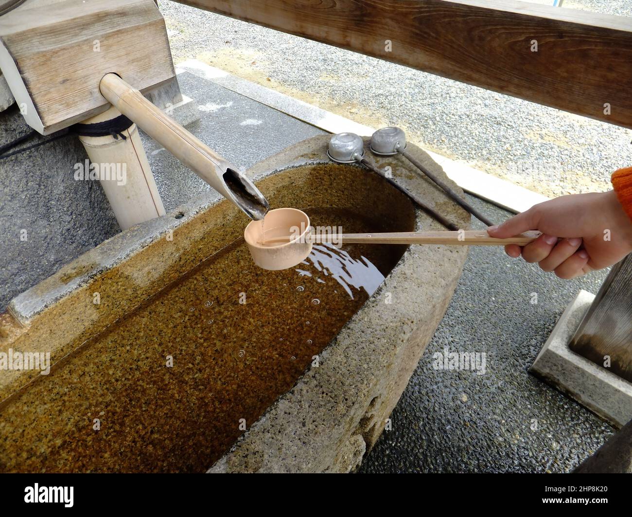 Hand holding a container for water in a traditional Japan temple at ...