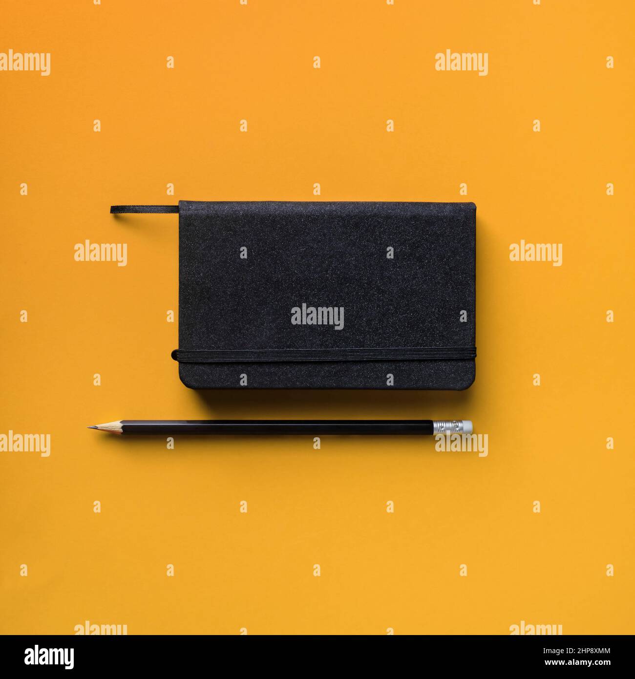 Photo of blank black notepad and pencil on yellow background ...