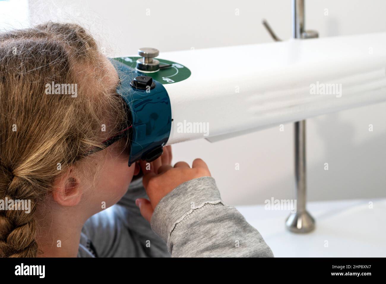 A girl is sitting in front of a device for stimulating vision.The ...