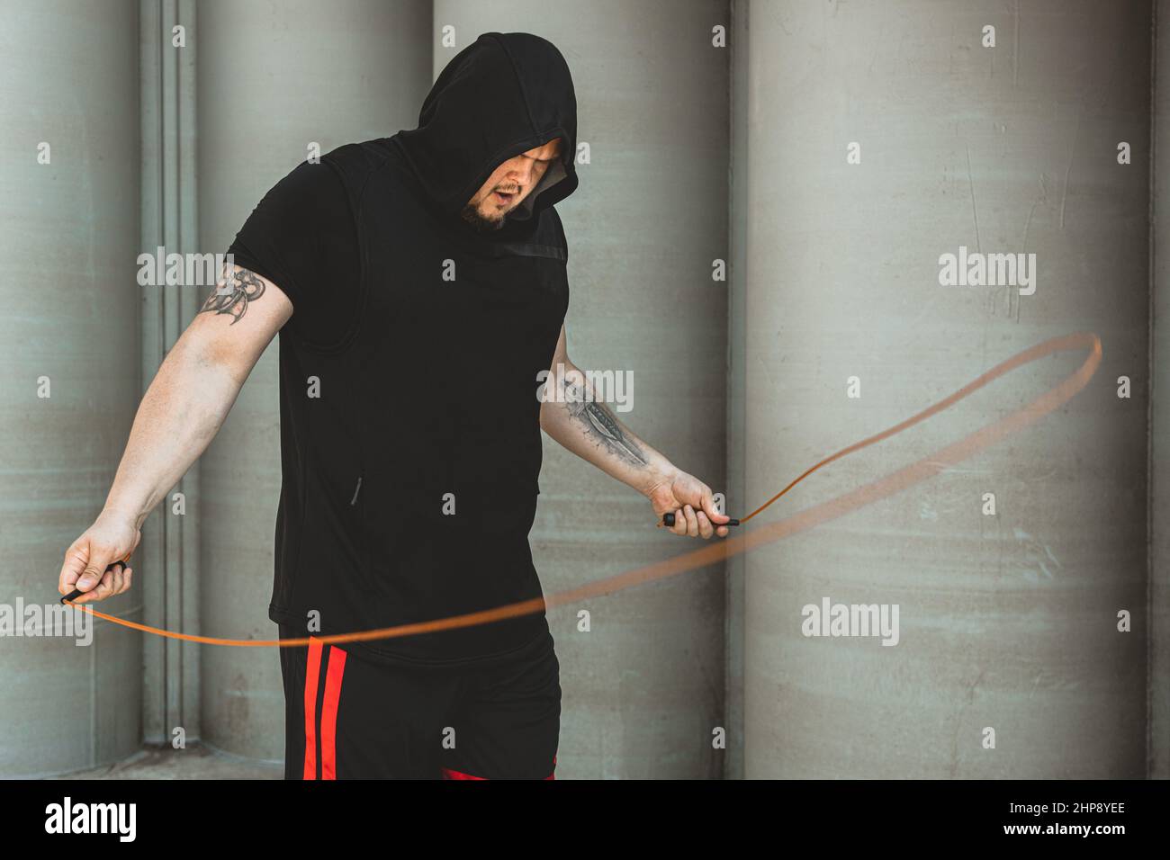 Caucasian man fighter training hard in the outdoors.. Man using rope ...