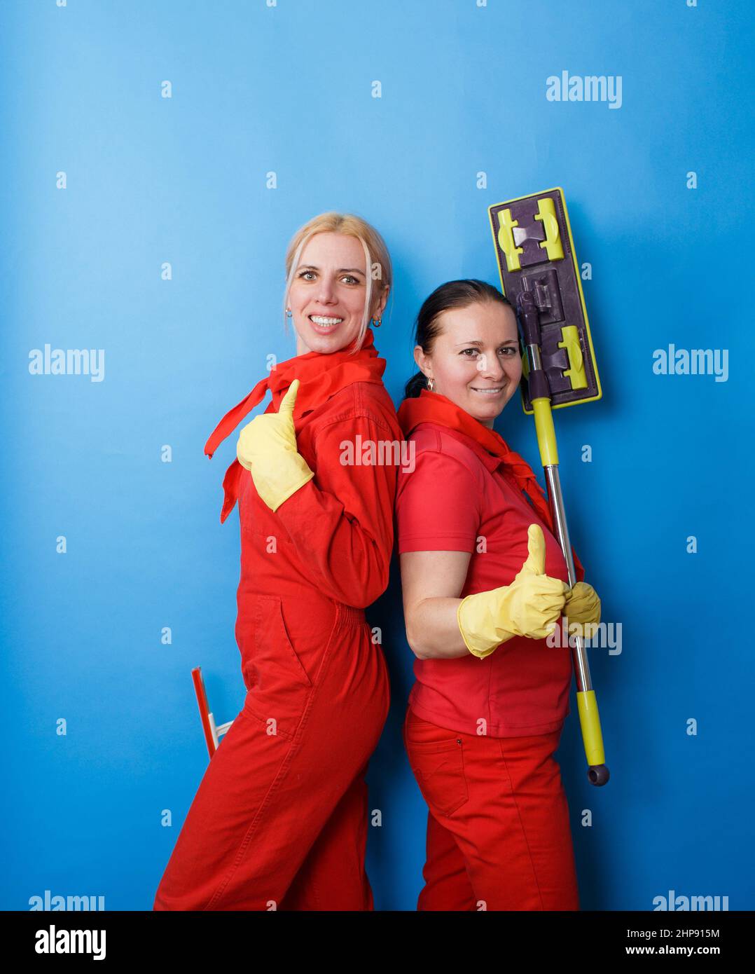 Two girls cleaning company workers in red uniforms smile on an isolated ...