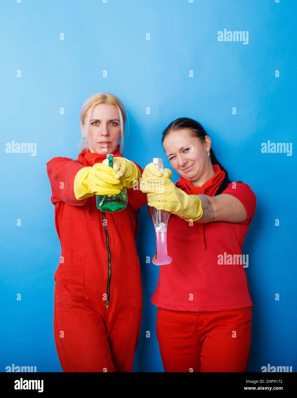Two girls cleaning company workers in red uniforms smile on an isolated ...