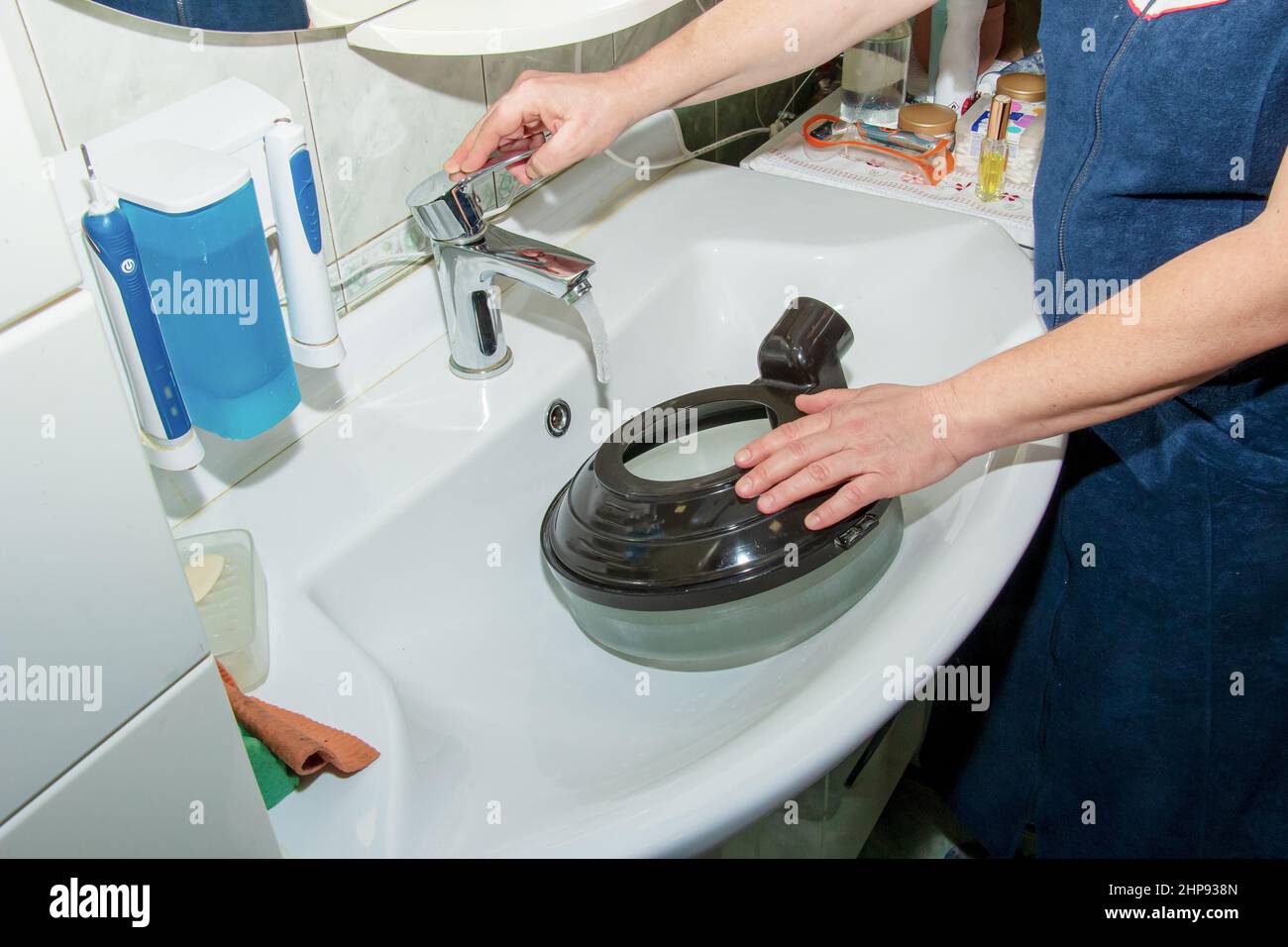 A woman draws clean water into the water tank for a washing vacuum ...