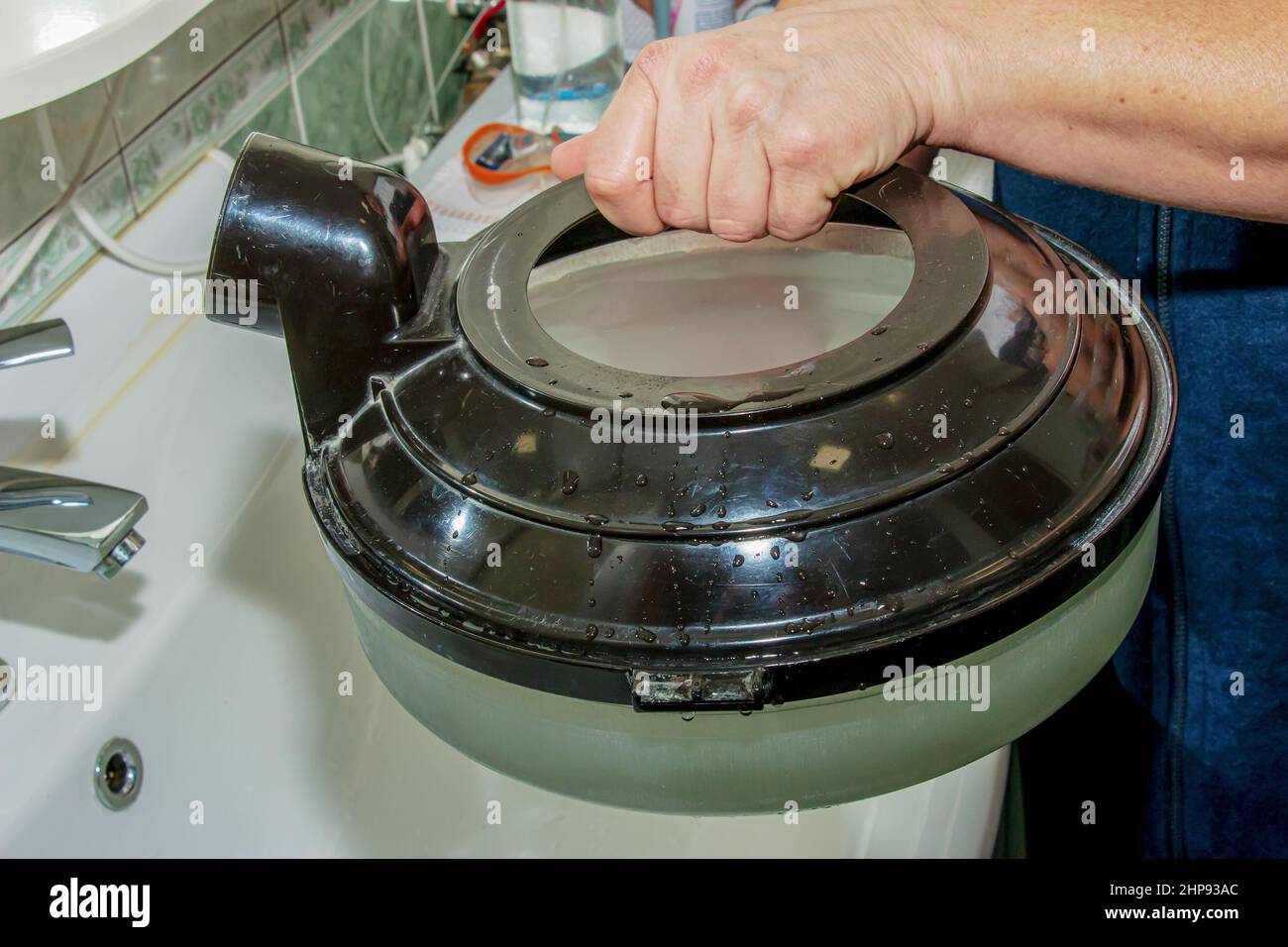A woman draws clean water into the water tank for a washing vacuum ...