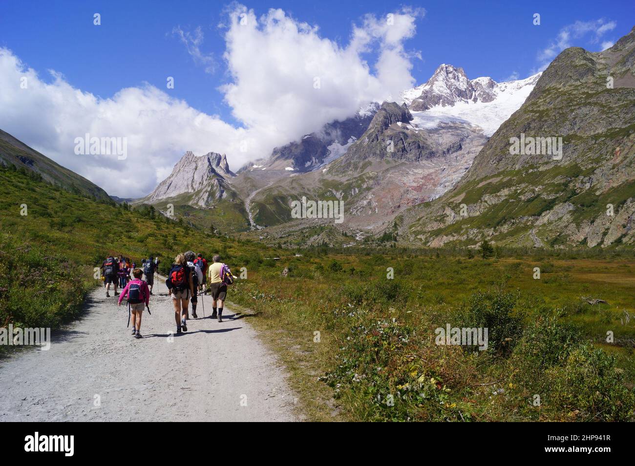 A group of trekkers walking on a mountain path in Val Veny, Aosta ...