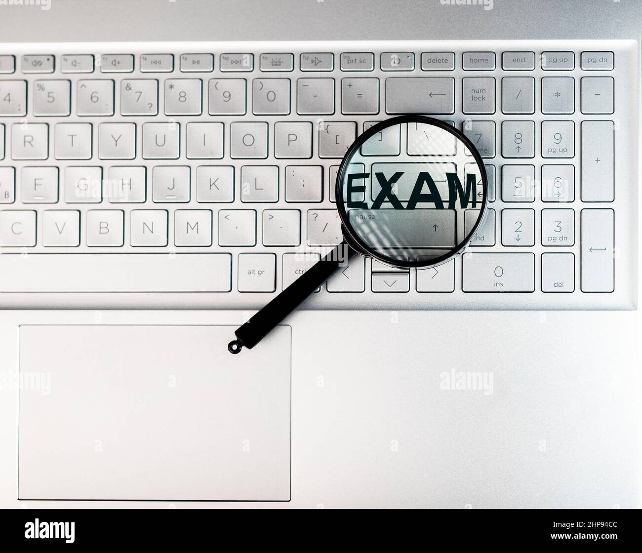 Word EXAM through magnifying glass and laptop. photo Stock Photo - Alamy