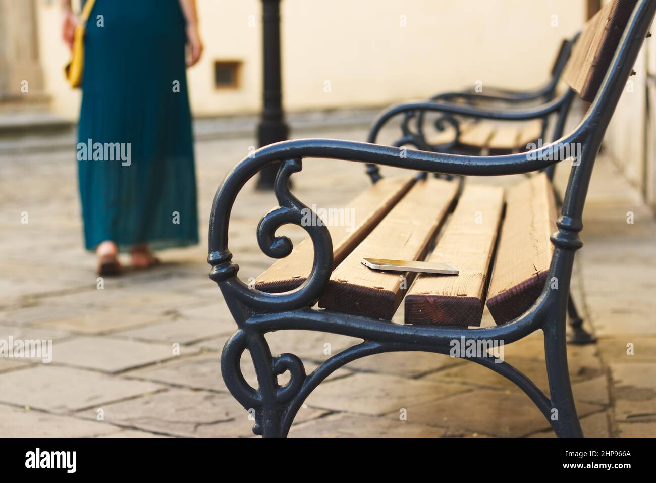Forgotten smartphone on bench in city. Woman is leaving from a bench ...