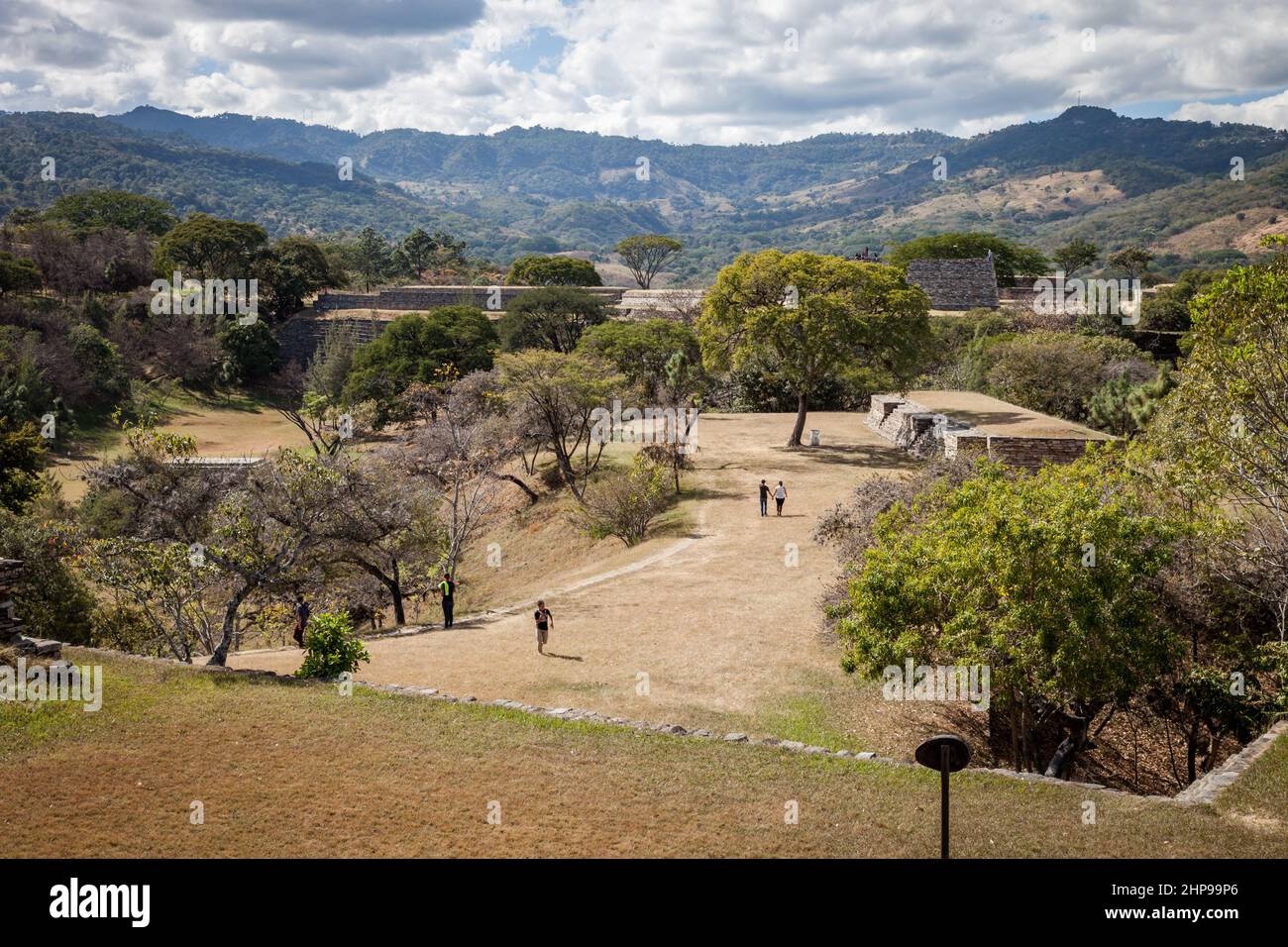 Visitors walk towards ruined structures at the historic Maya site of ...