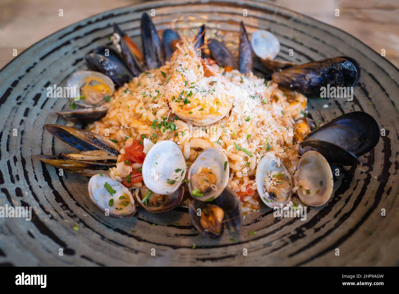 Shrimps on a seafood risotto on a circular plate. The meal has parmesan ...
