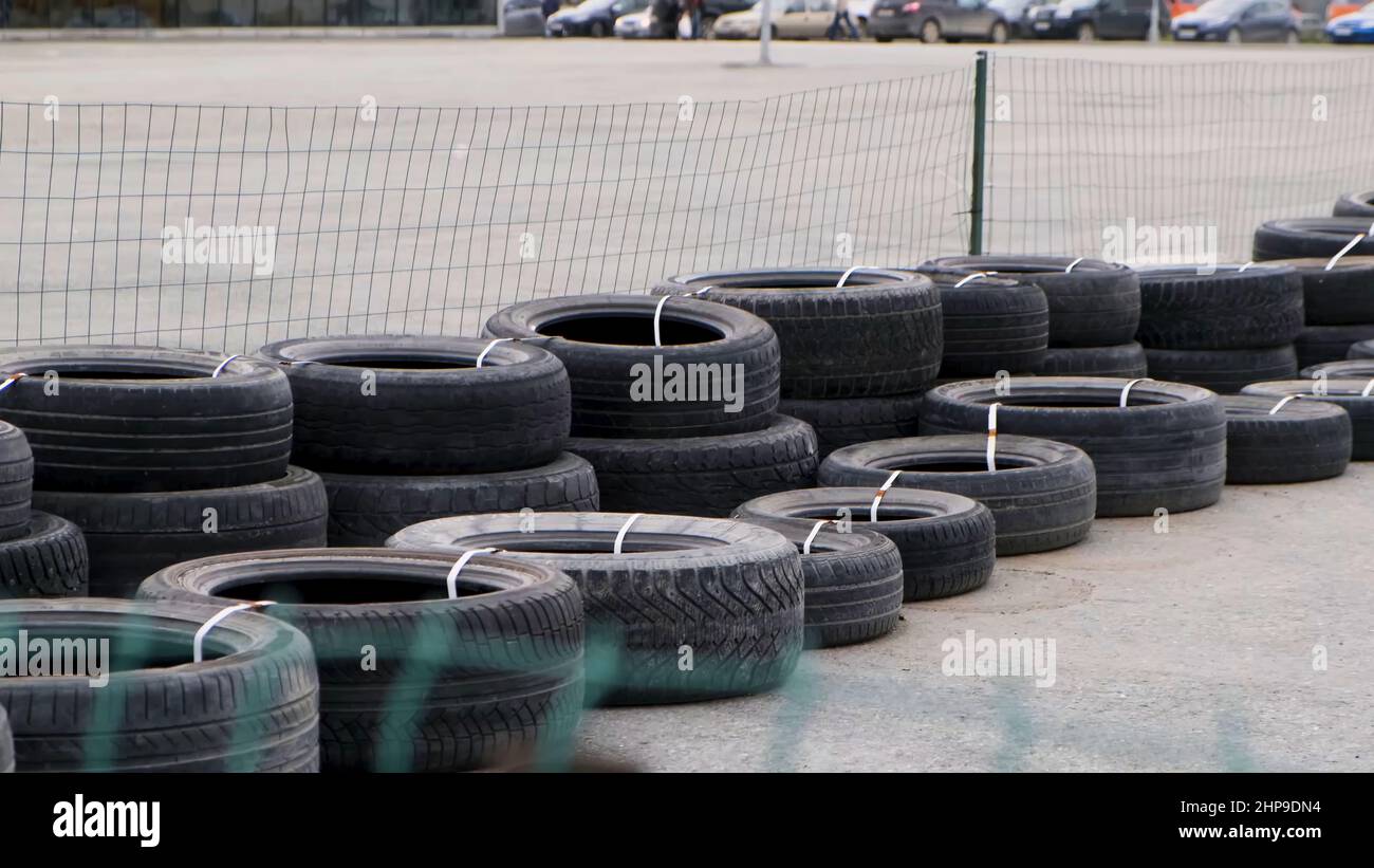 Safety barrier made of old black tires lying on a concrete pavement ...