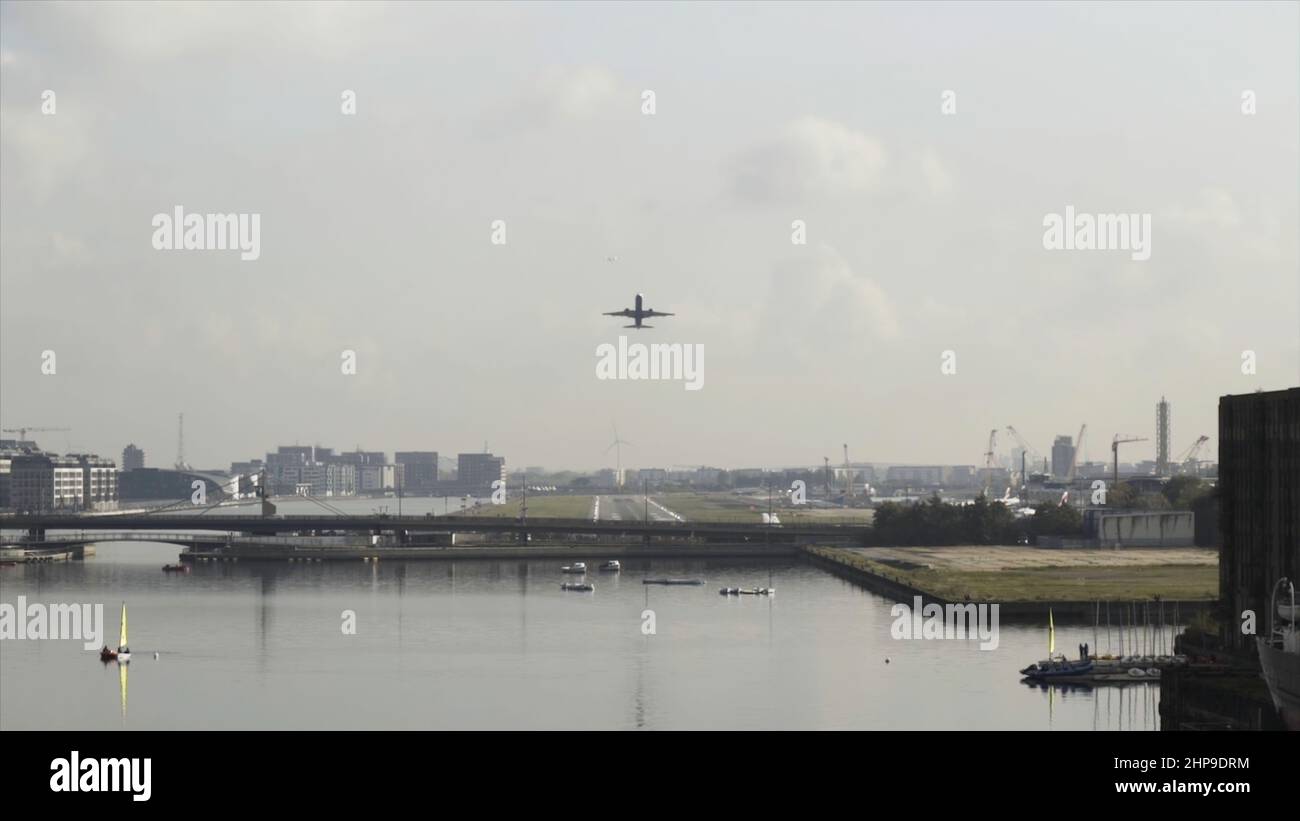 Airplane flying over the city, bridge and wide river on cloudy sky ...