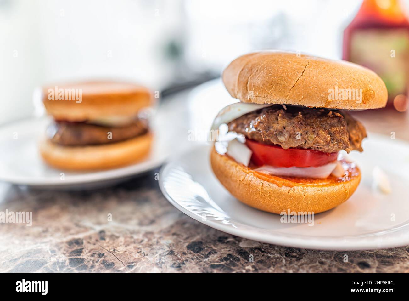 Two small burgers closeup of one with hamburger patty, buns onions and ...