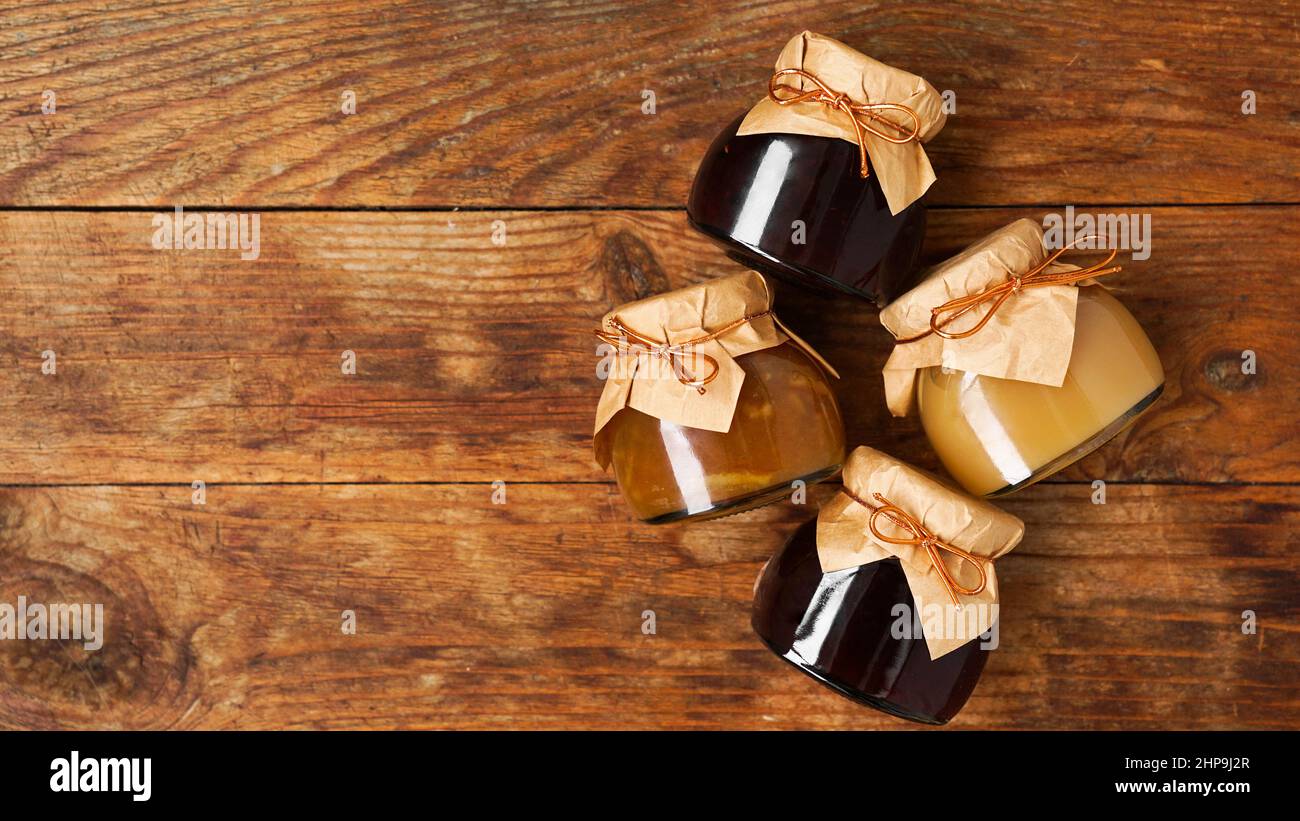 Four glass jars with different kinds of jam on wooden table. Homemade ...