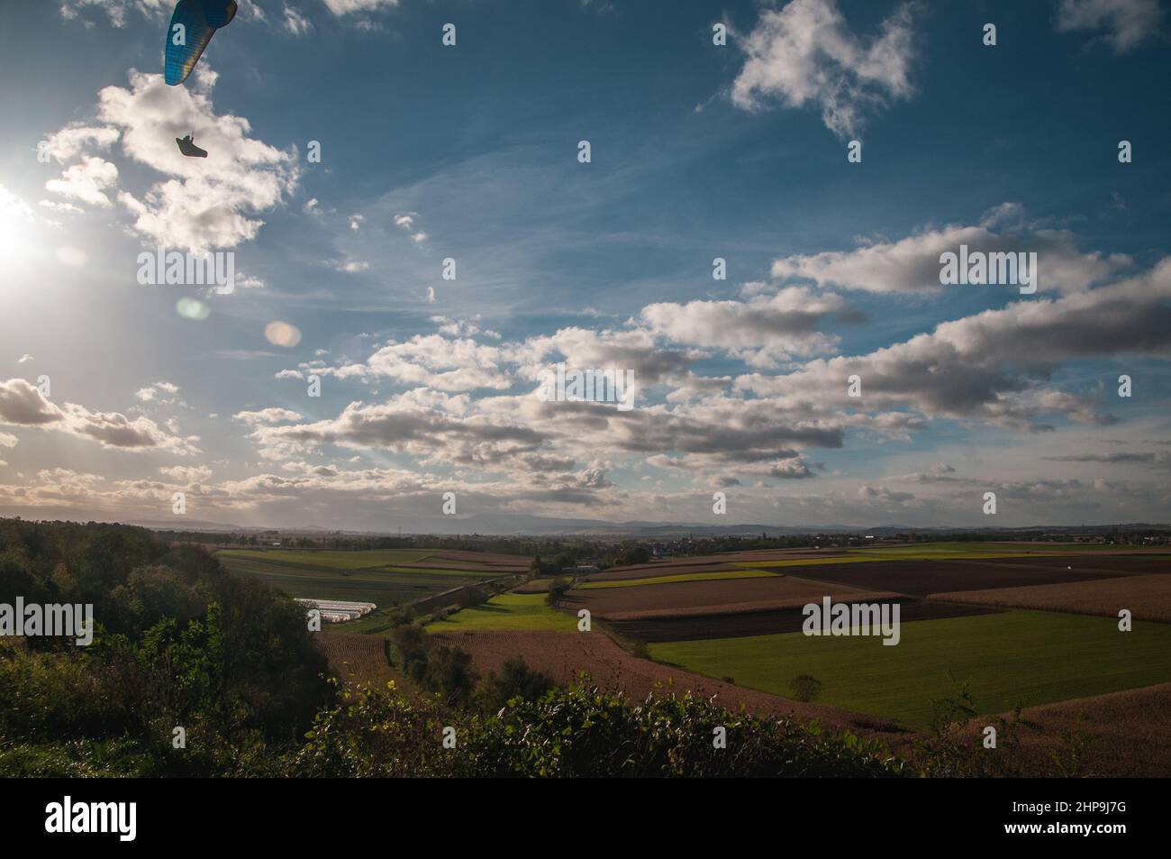 Aerial landscape with a field with a parachute man flying high in the ...