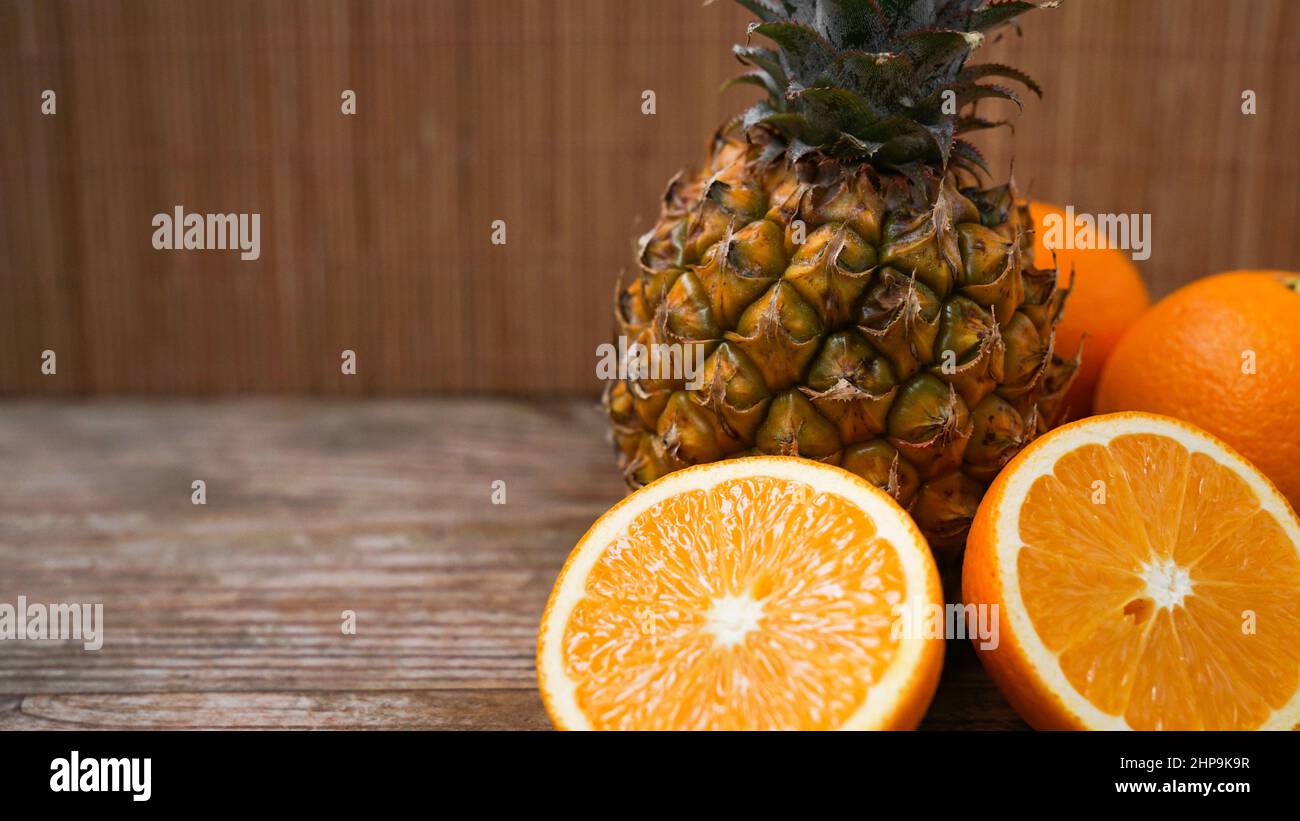 Pineapple and oranges. Tropical fruit on wooden table background with ...