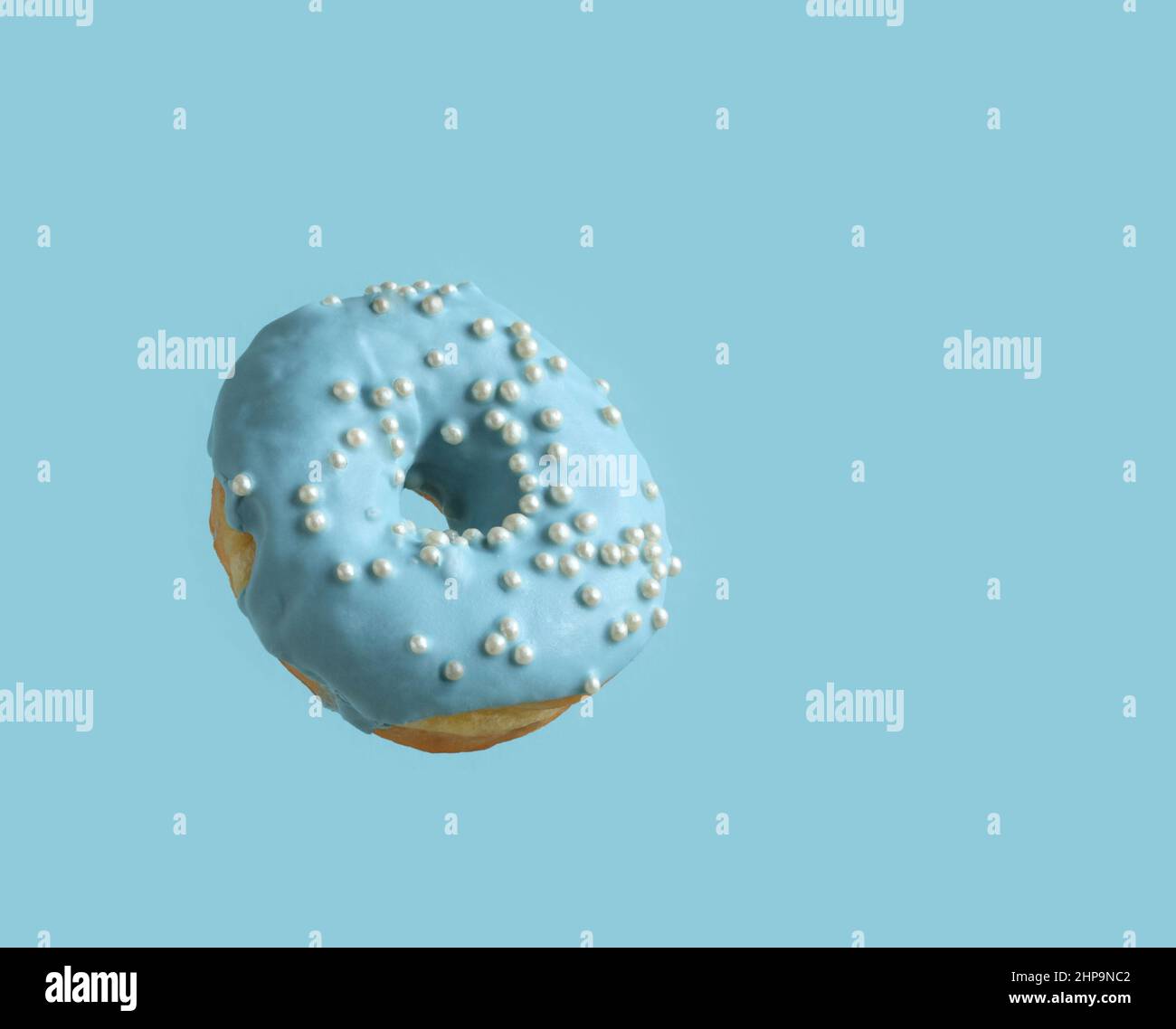 Donut covered with pale blue icing and sprinkled with pearl sugar beads ...