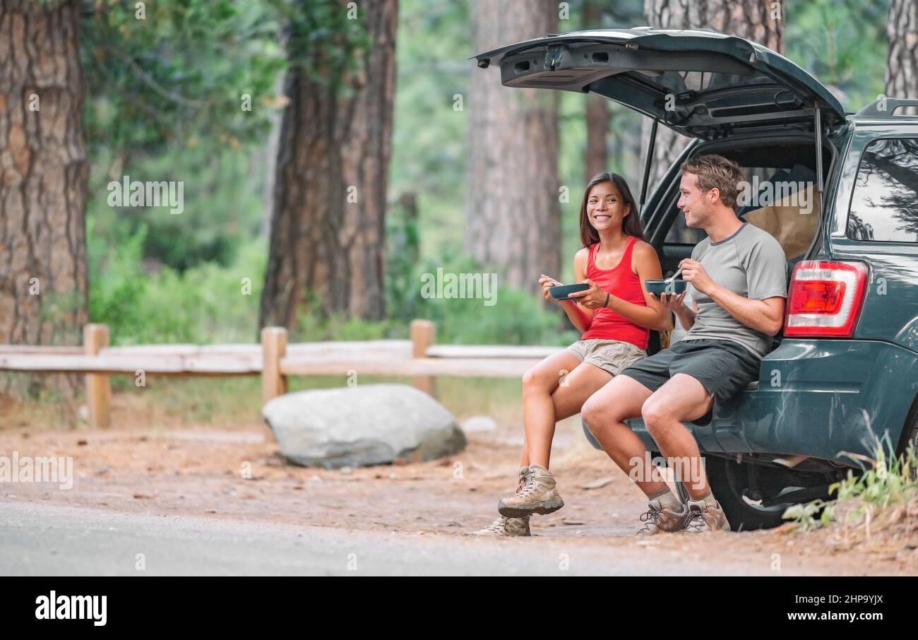 Road trip couple tourist eating food lunch at back of car on summer ...
