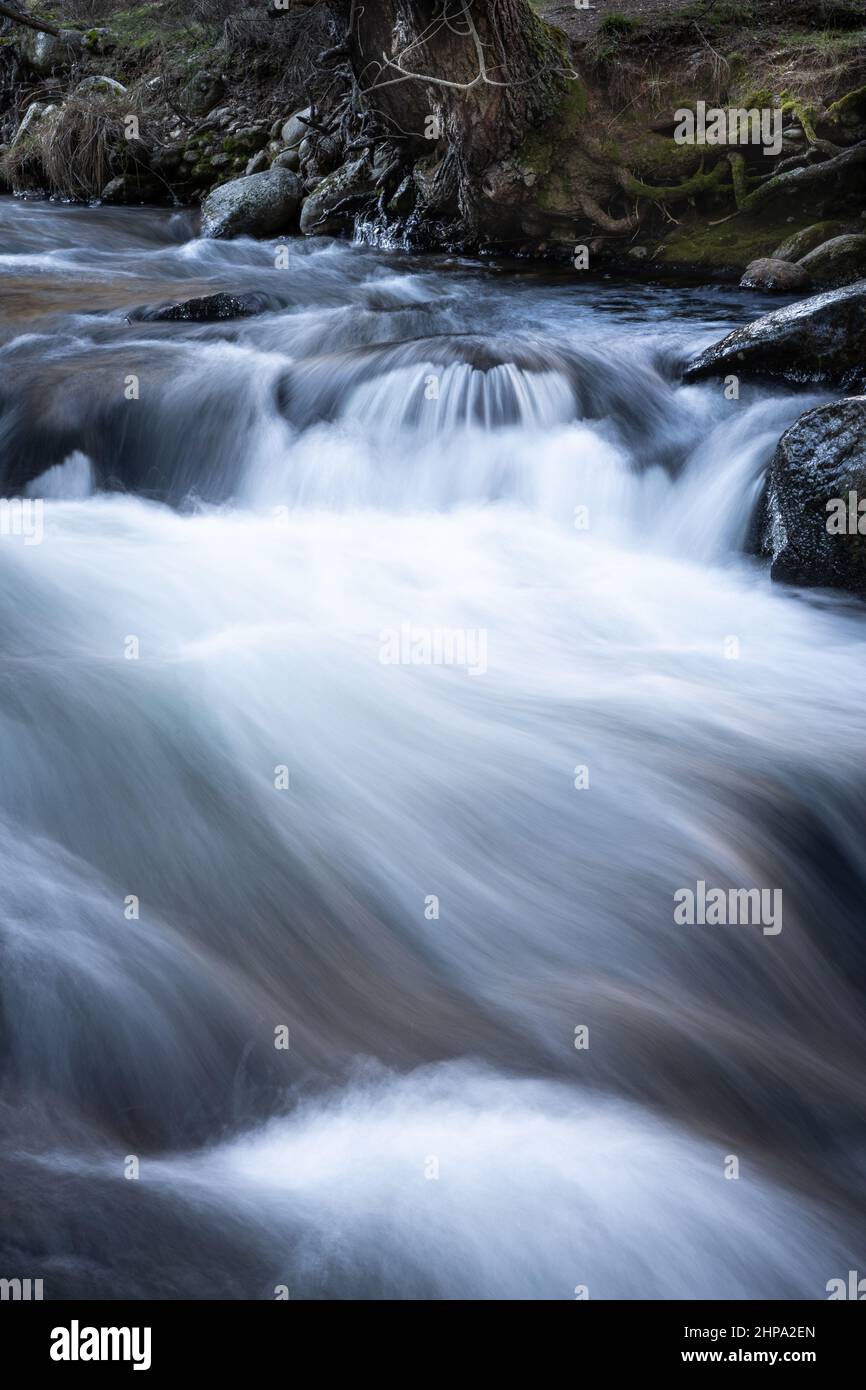 Vertical photo of a water stream flowing over and among rocks in nature ...