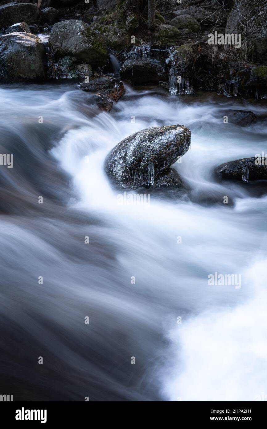 Vertical photo of a water stream flowing over and among rocks in nature ...