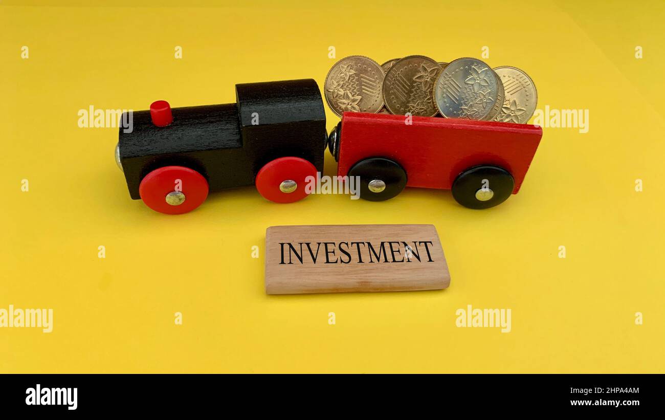 Toy train carry gold coins with investment word on wooden block ...