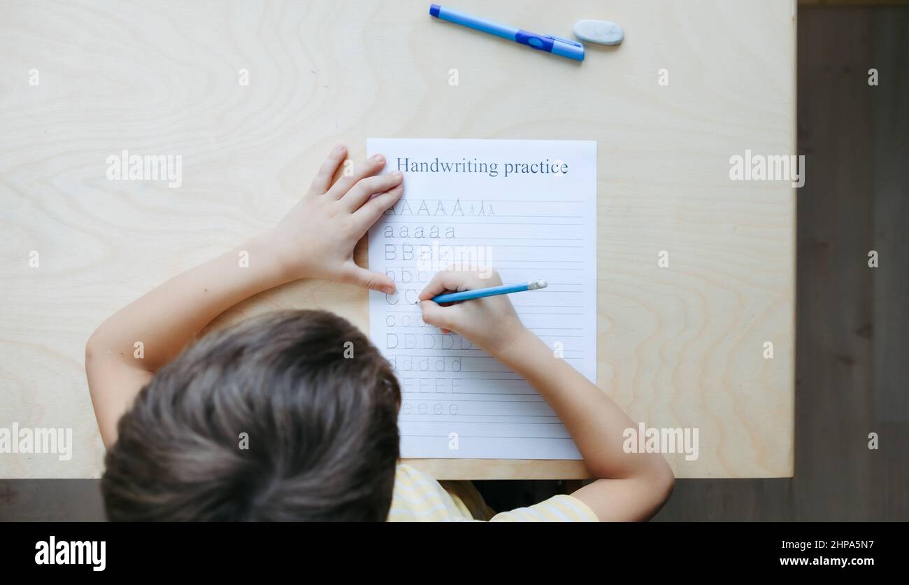 A schoolboy doing math lesson sitting at desk in the children room ...