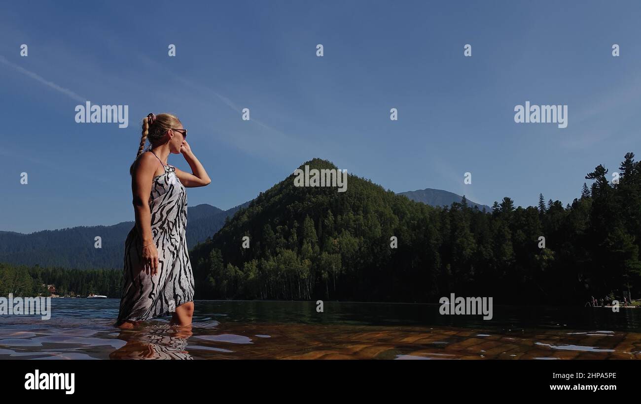 Woman walk on water on pier in sunglasses and a boho silk shawl. Girl ...