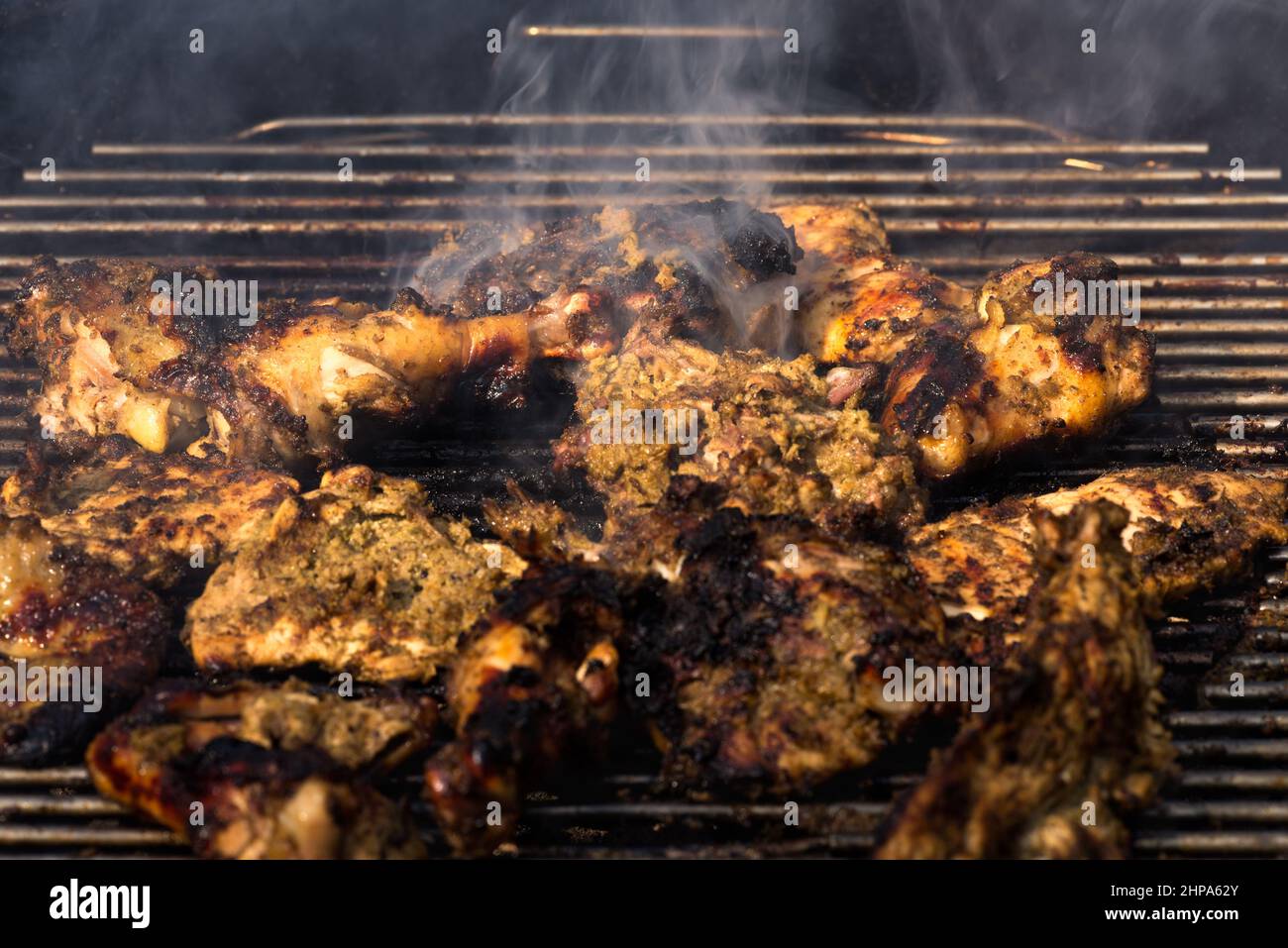 Grilling traditional Jamaican spicy jerk chicken with over wood fire ...