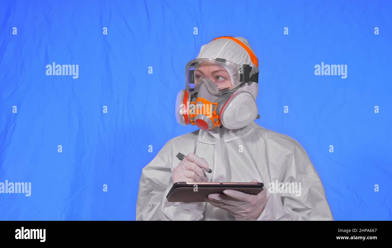 Scientist virologist in respirator makes write in an tablet computer ...