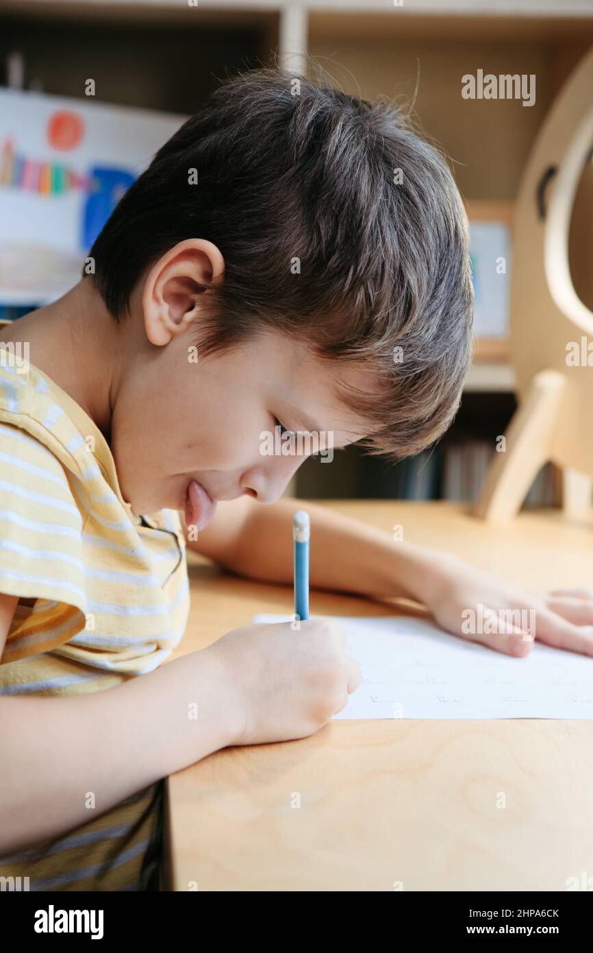 A schoolboy doing math lesson sitting at desk in the children room ...