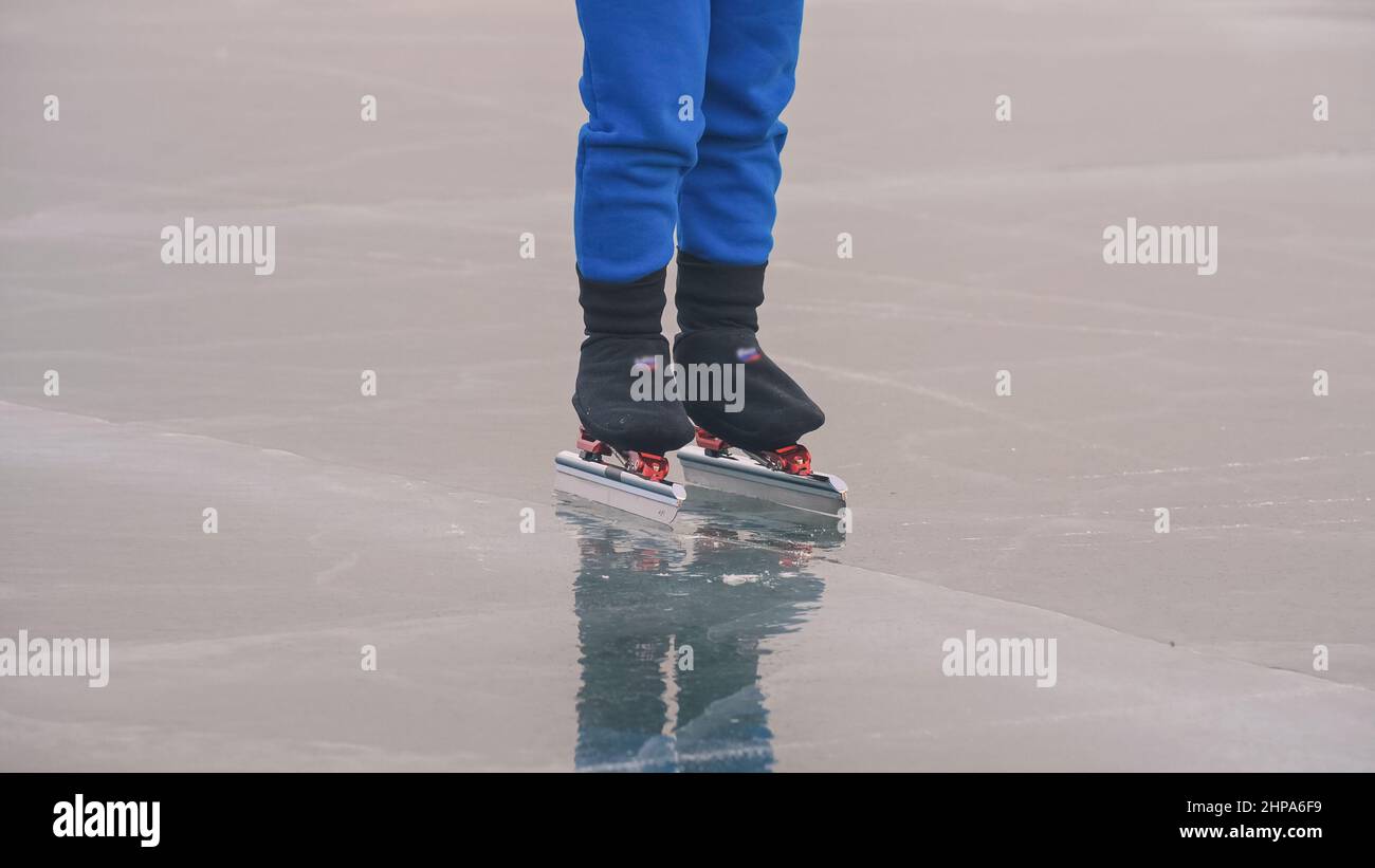The child train on ice speed skating. The legs in skates close up. The ...