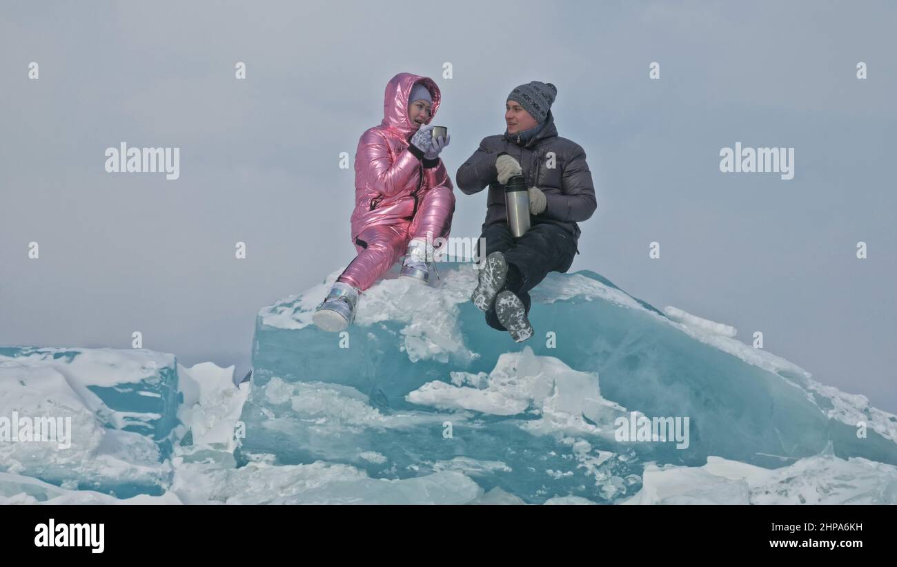 Couple has fun winter walk against background of ice of frozen lake ...