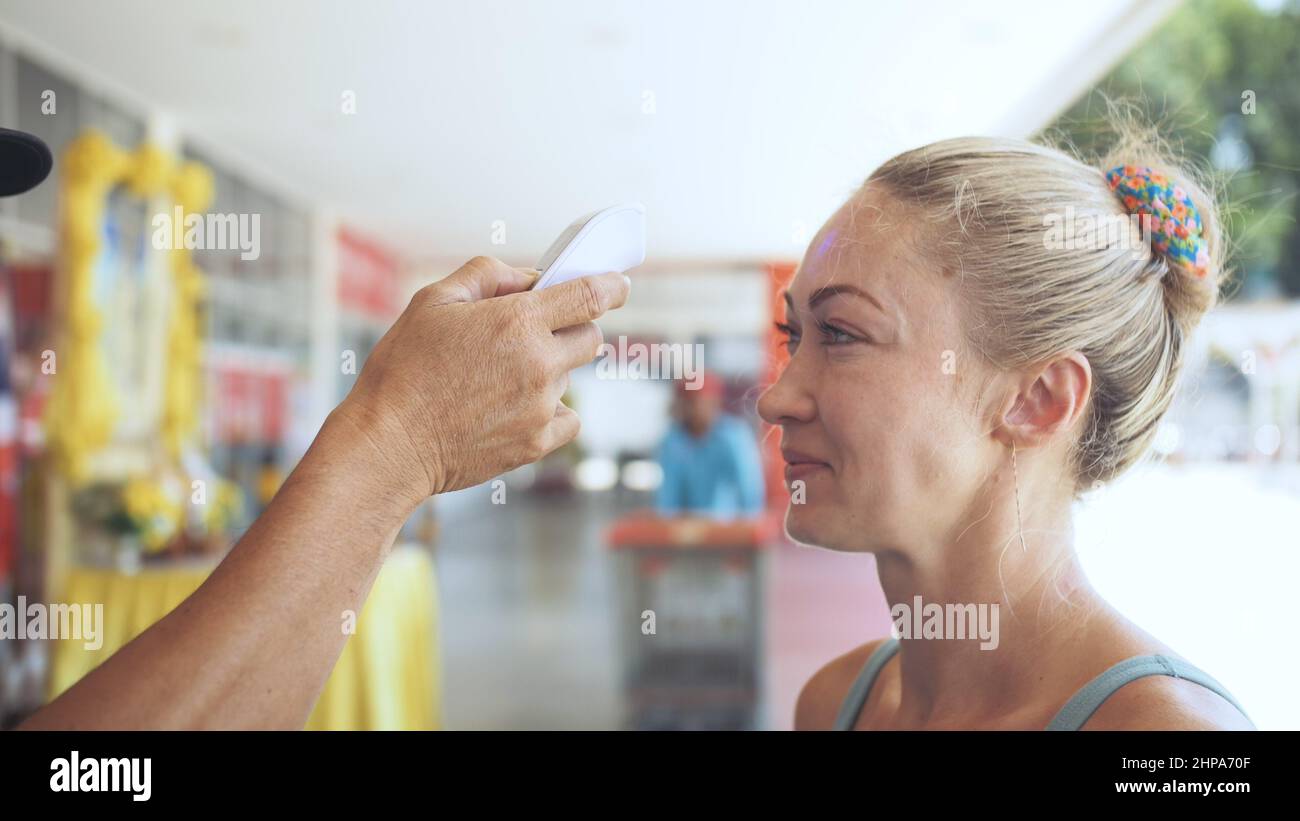 Temperature check at a supermarket of woman, grocery store with thermal ...
