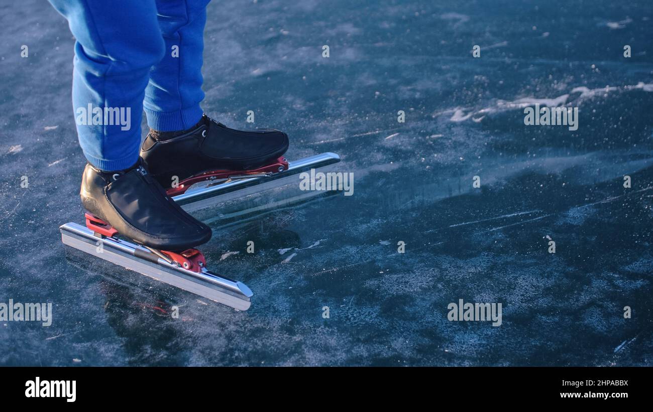 The child train on ice speed skating. The legs in skates close up. The ...