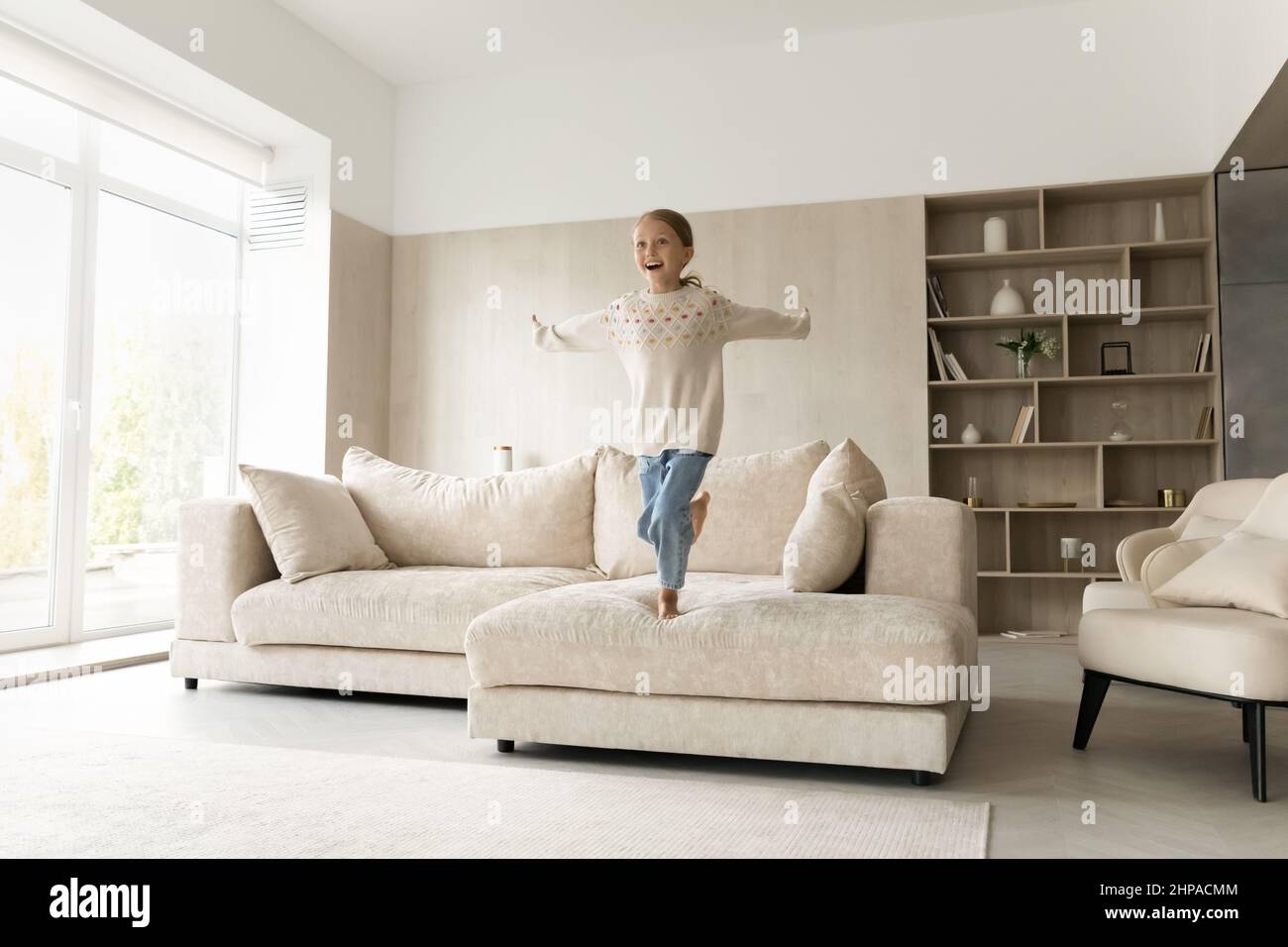 Excited cheerful girl kid jumping on comfortable couch Stock Photo - Alamy