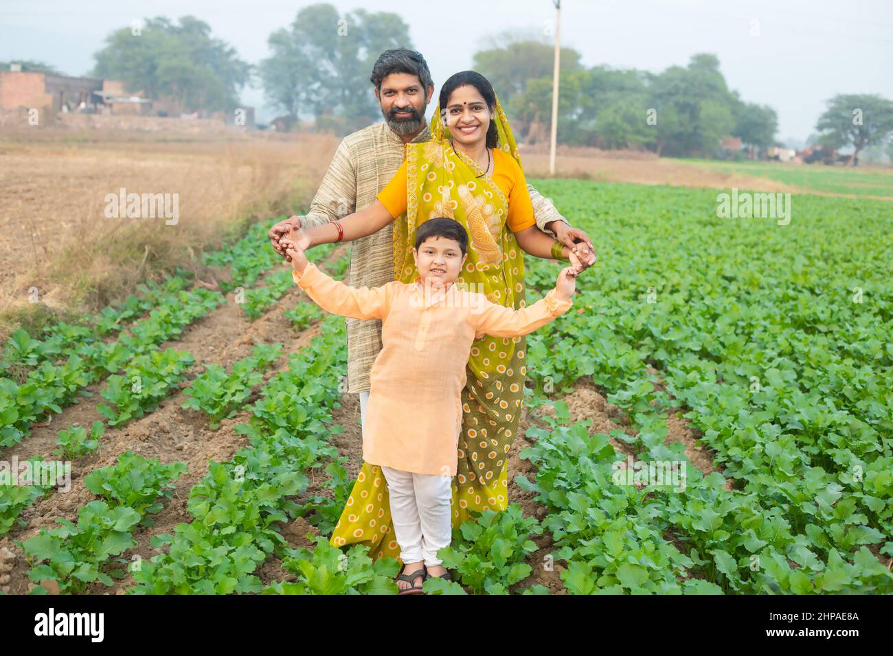 Portrait happy rural Indian family standing at agricultural field ...