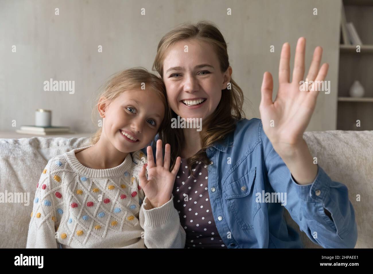 Happy sweet daughter kid and young mom waving hand hello Stock Photo ...