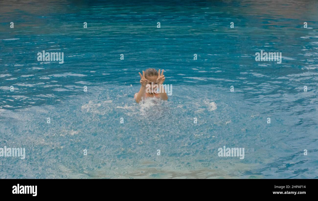 The little cute girl have fun in the swim pool. The child enjoy summer ...