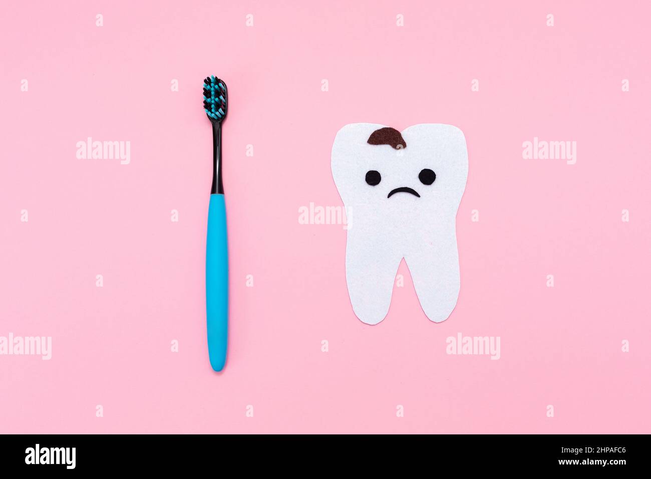 A plastic toothbrush and a felt-cut out sad tooth with decay. Flat lay ...