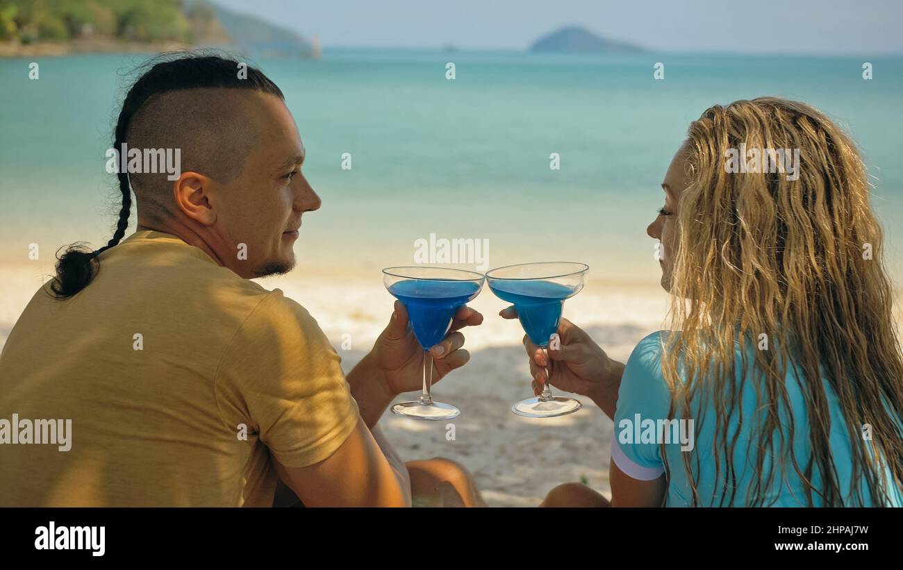 The love couple is holding a glass of blue curacao cocktail, on sea ...
